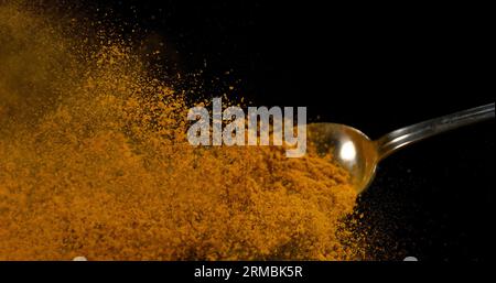 Spoon and Curry Powder falling from Spoon against Black Background ...