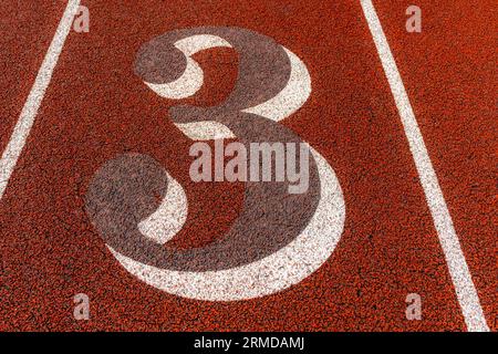 Close up lane number three, 3, on a new black running track with white ...