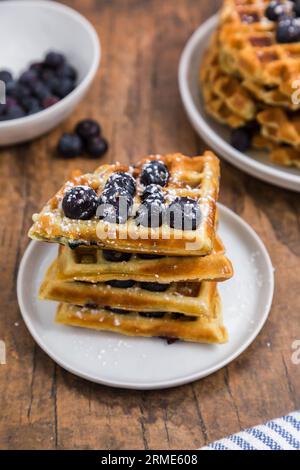 Delicious Belgian waffles with blueberries in plate and honey on table ...