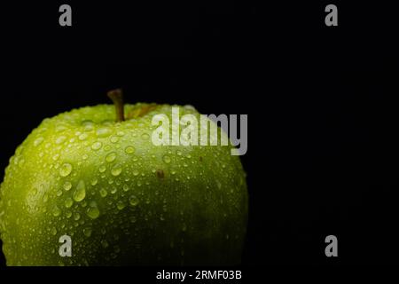 Micro close up of green apple with water drops and copy space on black ...