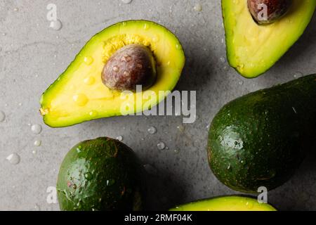 Micro close up of avocados with water drops and copy space on grey ...
