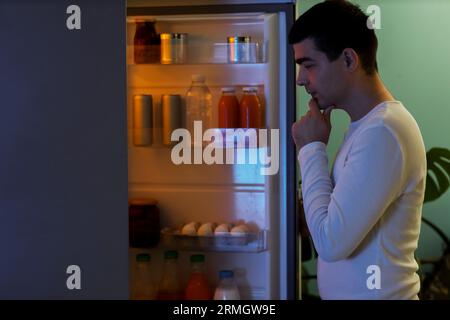 Hungry young man near open fridge in kitchen at night, back view Stock ...