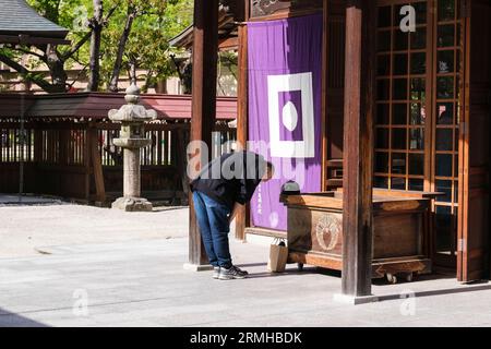 Japan, Fukuoka. Worshipper at Kego Shinto Shrine. Roof Shows Chigi V ...