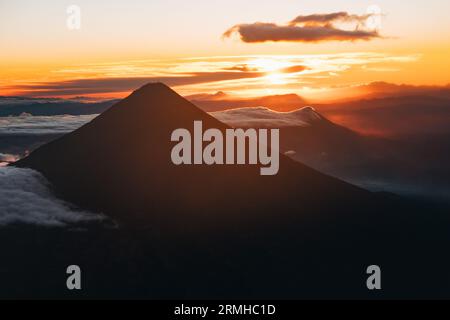 The sun rises from behind Agua Volcano in Guatemala, casting a dramatic ...