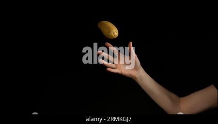 Hand of Woman Throwing a Potatoe against Black Background Stock Photo ...