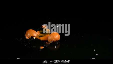 Egg falling and Exploding on black background Stock Photo - Alamy
