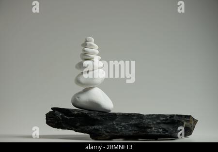 white smooth stones balanced over one black flat stone Stock Photo - Alamy