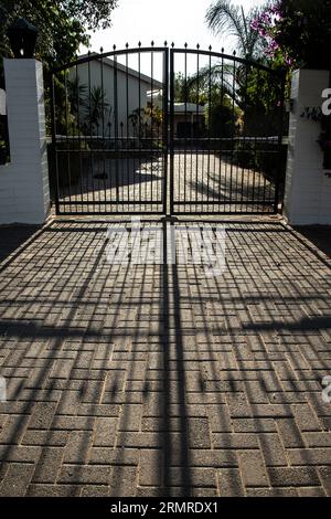 The shadows from a pair of closed; black, sinister wrought iron gates ...