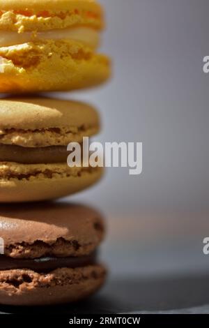 Brown and yellow toned macarons stacked on black background, close up ...