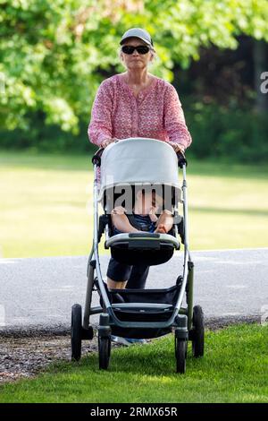 A young family with a baby in a stroller admire a view of a river while ...