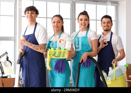 Young janitors with cleaning supplies in room on Christmas eve Stock ...