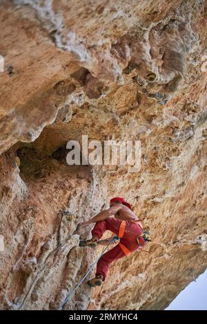 Low angle of muscular male alpinist hanging on climbing wall while ...