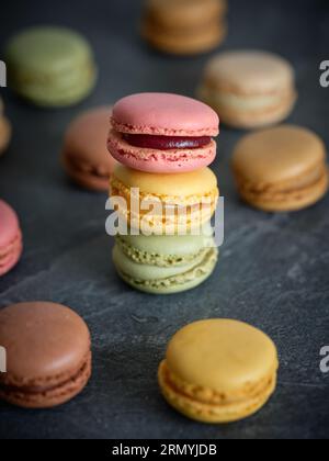 French macaroons of various flavors on a white plate on wooden table ...