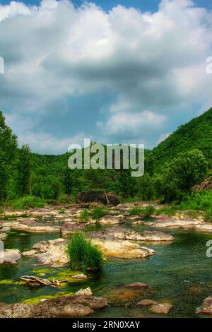 A scenic view of a reflective river with green shoreline trees at ...