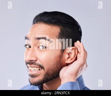 Deaf, cochlear and asian man ear in studio with hearing aid, audio and ...