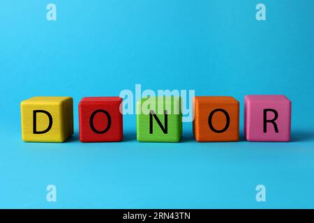 Word Donor made of colorful wooden cubes and stethoscope on light blue ...