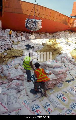 Workers unload sacks of rice from a relief ship in the port of ...