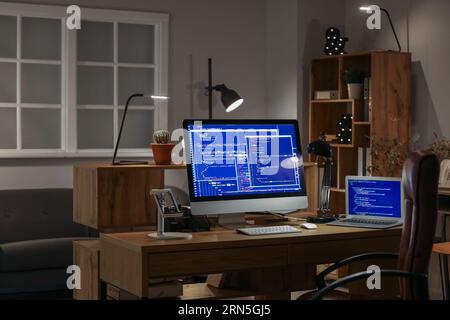 Interior of dark office with programmer's workplace and shelf units at ...
