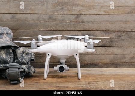 Modern quadcopter, military cap and body armor on wooden background ...