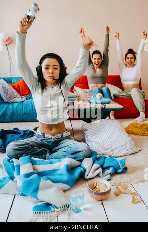 Young Asian female gamer playing video game with controller relaxing on ...