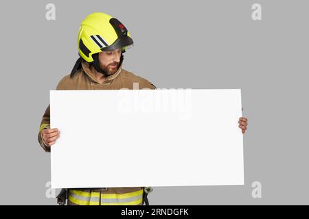 Focused male firefighter looking at blank banner in front. Front view ...