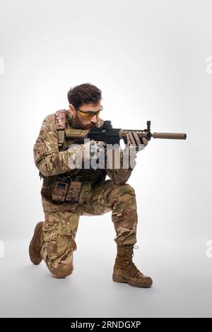 Focused special operations fighter aiming from assault rifle indoors ...