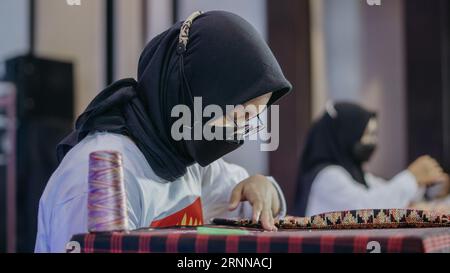 A woman is weaving cloth, or so-called traditional tapis cloth Stock ...