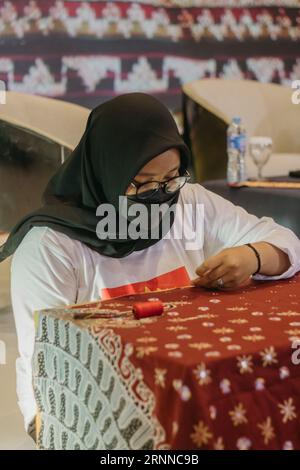 A woman is weaving cloth, or so-called traditional tapis cloth Stock ...