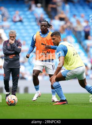 Manchester City's Jeremy Doku, centre, challenges for the ball with ...