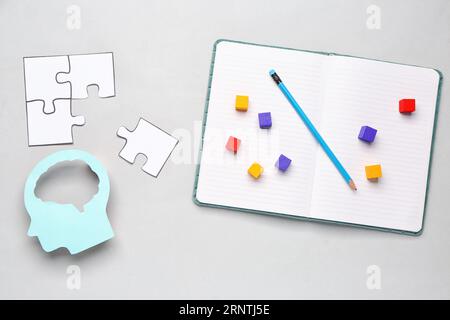 Notebook with cubes, paper human head and puzzle pieces on light ...