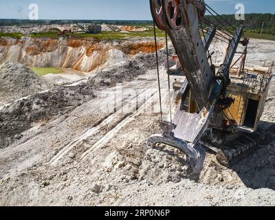 Bucket of excavator digs chalk pile in quarry on sunny day Stock Photo ...