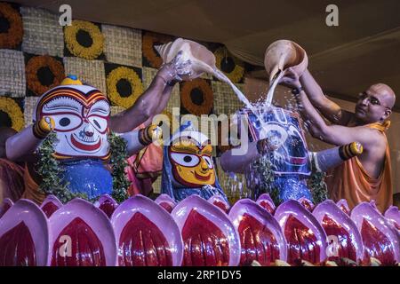 Hindu priests pour milk on top of deities Lord Jagannath, Balabhadra ...