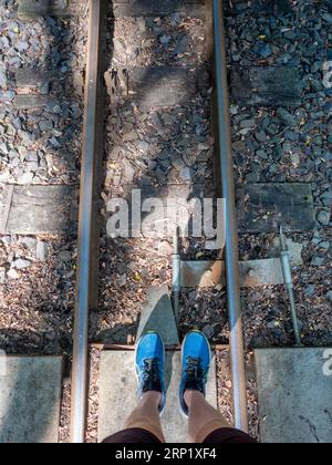 Railroad rails and feet with running sneakers. Upper view down to legs ...