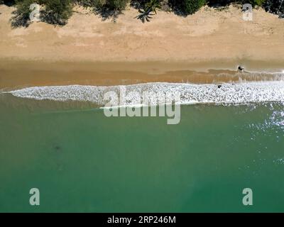 A beautiful shot of sea waves crashing on a beach surrounded by cliffs ...
