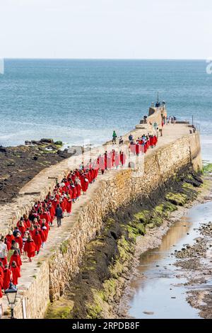 People walking along St Andrews harbour wall at high tide Stock Photo ...