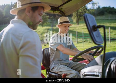 Farmer father letting his son drive the tractor. Boy growing up and ...