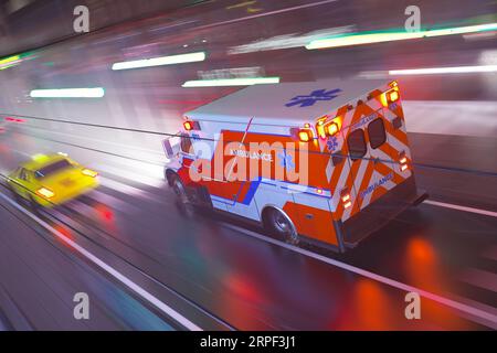 An emergency ambulance on the signal goes through a city streets during ...