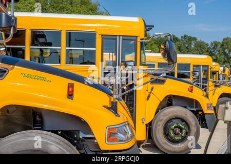 Yellow electric school bus plugged in at a charging station Stock Photo ...
