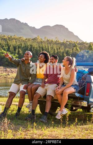 Group Of Friends With Backpacks In Pick Up Truck On Road Trip By Lake ...
