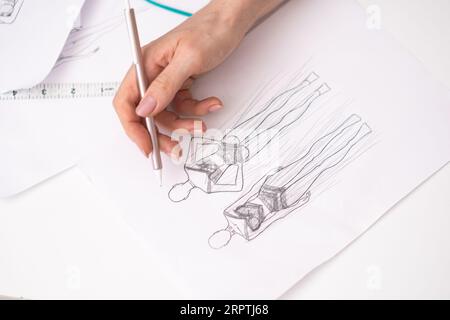 Designer works on dress in studio filled with sewing supplies and ...
