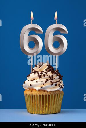 Birthday number 66 - Candle lit on blue background Stock Photo - Alamy