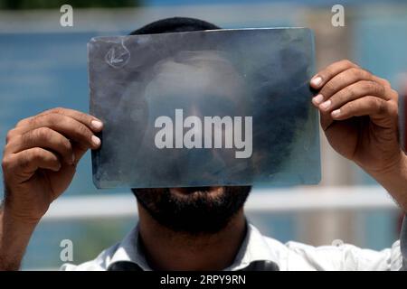 A Pakistani holds x-ray sheet to observe the partial solar eclipse at ...