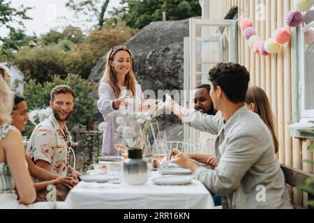 Woman passing plate of food at table Stock Photo - Alamy