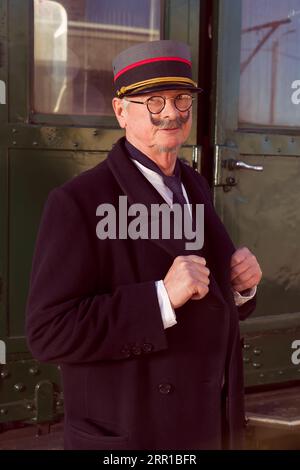 Reenactment scene of a vintage railway conductor at the departure of ...