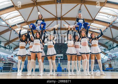 Cheerleader doing a split while other girls holding her up in the air ...