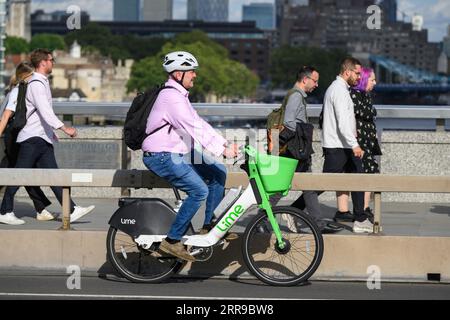 A man commuting on a Lime electric hire bike across London Bridge ...