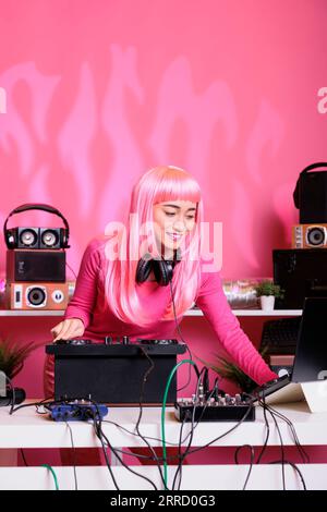 Asian musician standing at dj table mixing electronic sounds with ...