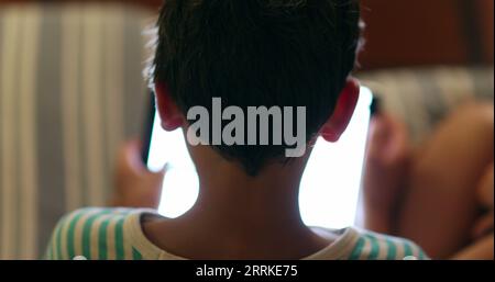 Back of child head staring at screen device at night Stock Photo - Alamy