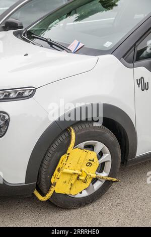 Car wheel blocked by a yellow metal lock or clamp. Vehicle illegal ...