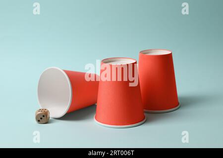 Three red cups and dice on light blue background. Thimblerig game Stock ...